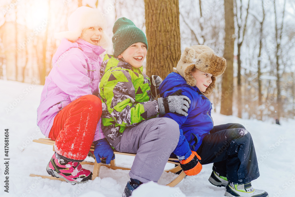 Little girl and two boys enjoy a sleigh ride. Child sledding. Cute kid ...