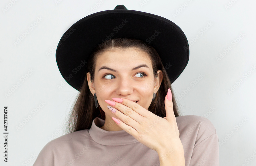 Pretty young female covering mouth with hand and cheerfully laughing at ...