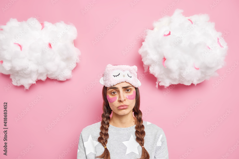 Upset dejected woman with two pigtails looks sadly at camera wears ...