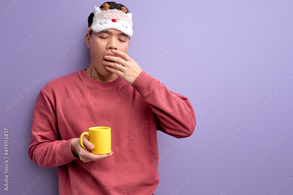 tired asian student with mug in hands yawning, want to sleep before ...