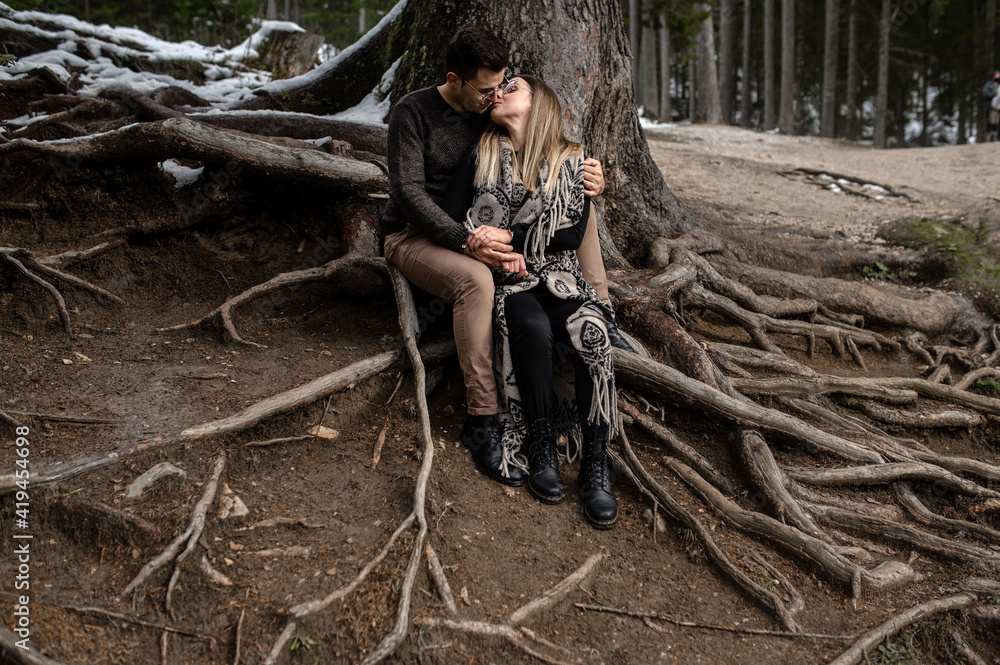 Full body of positive gentle couple sitting near tree and hugging and ...