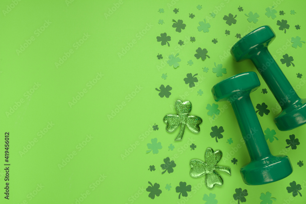 Two heavy dumbbells and Irish shamrock leaf clover. Healthy fitness gym ...