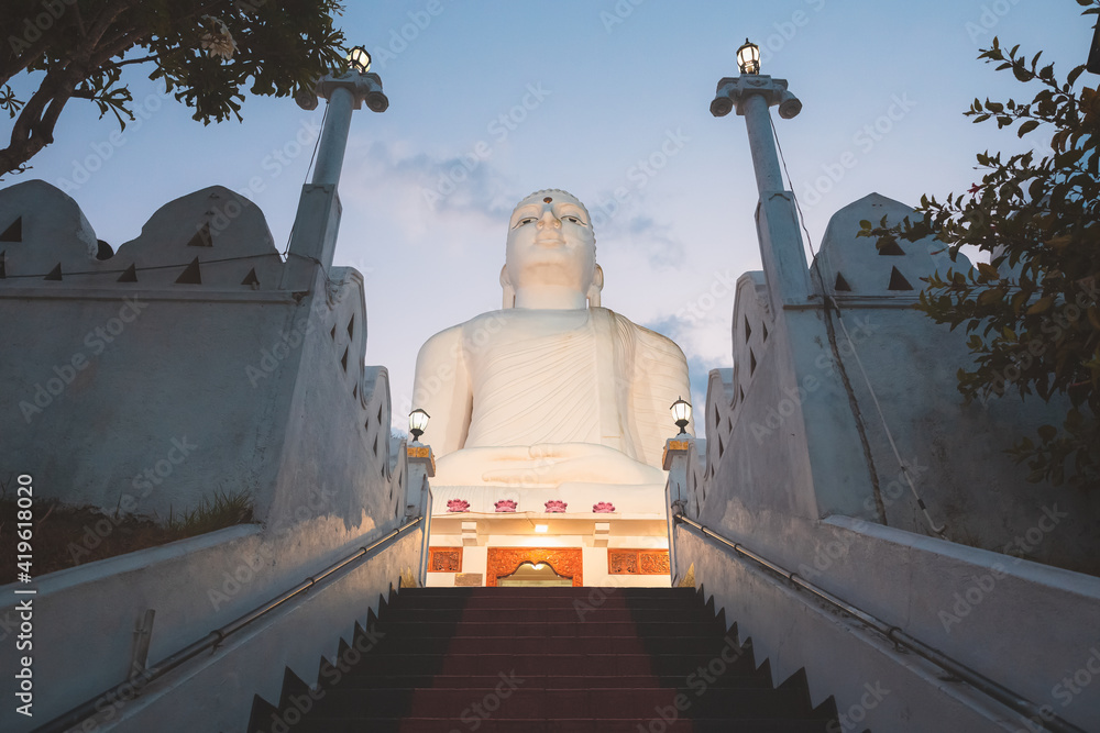 Steps leading up to the giant white Buddha statue illuminated at night ...