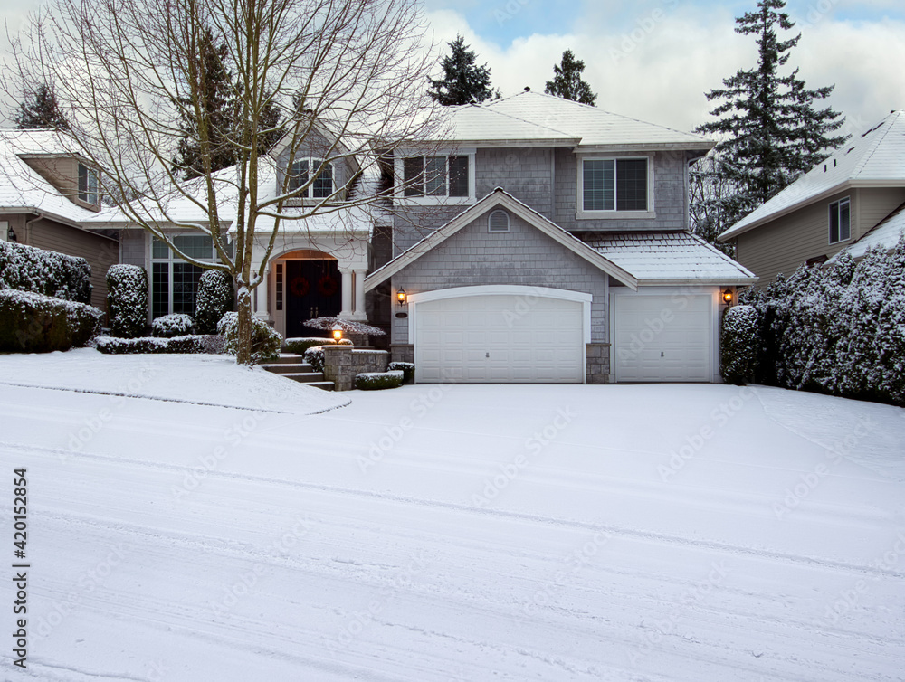 Curb view of a home with freshly fallen snow during early winter season ...