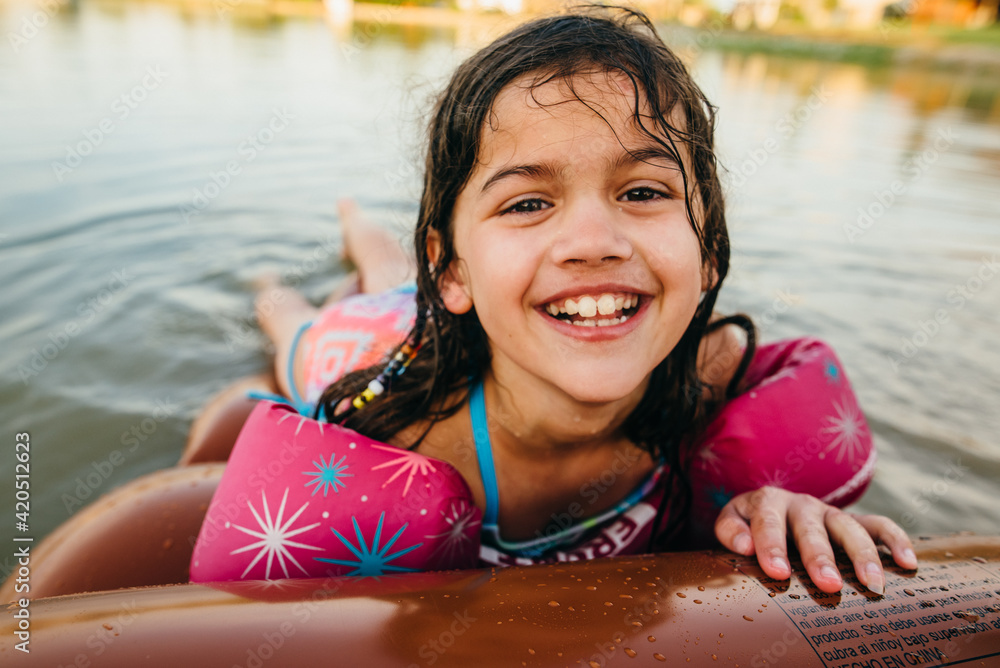Girl smiling laying on raft. Stock Photo | Adobe Stock