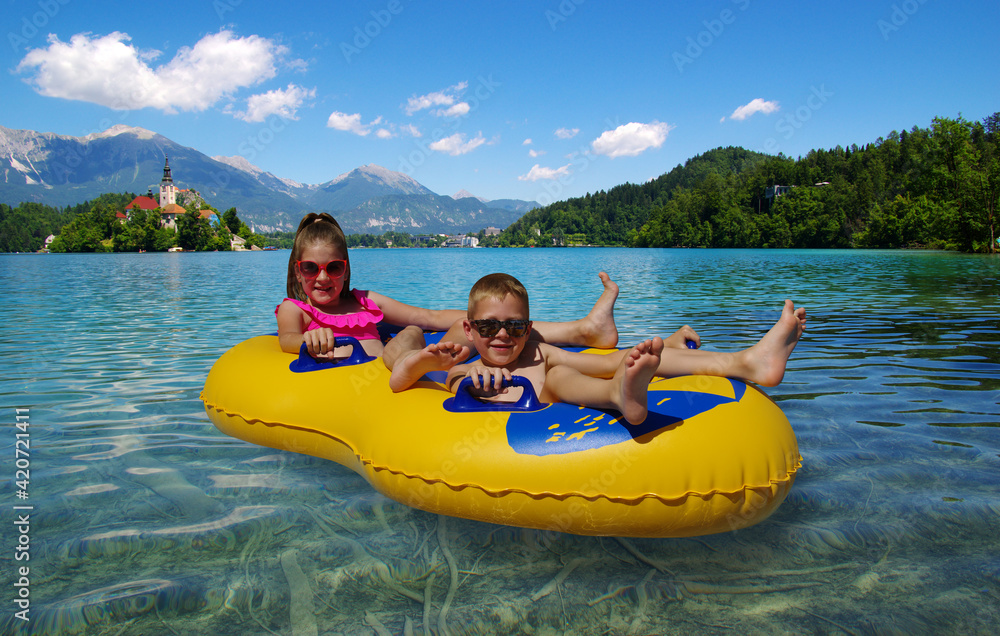 Boy and girl on inflatable float in lake. Little children floating in ...