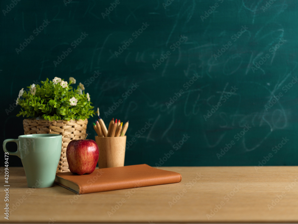 Study table with notebook, apple, pencils and plant pot in classroom ...
