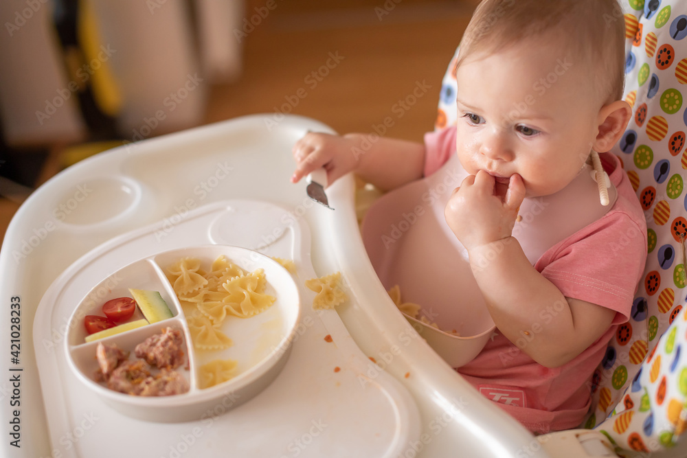 One year old girl having balanced meal in baby eating chair, healthy ...