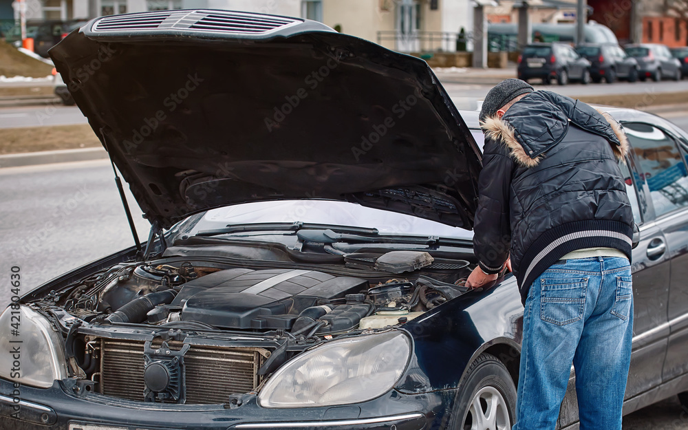 Foto de Stock Man try fix car breakdown on road side at city street ...