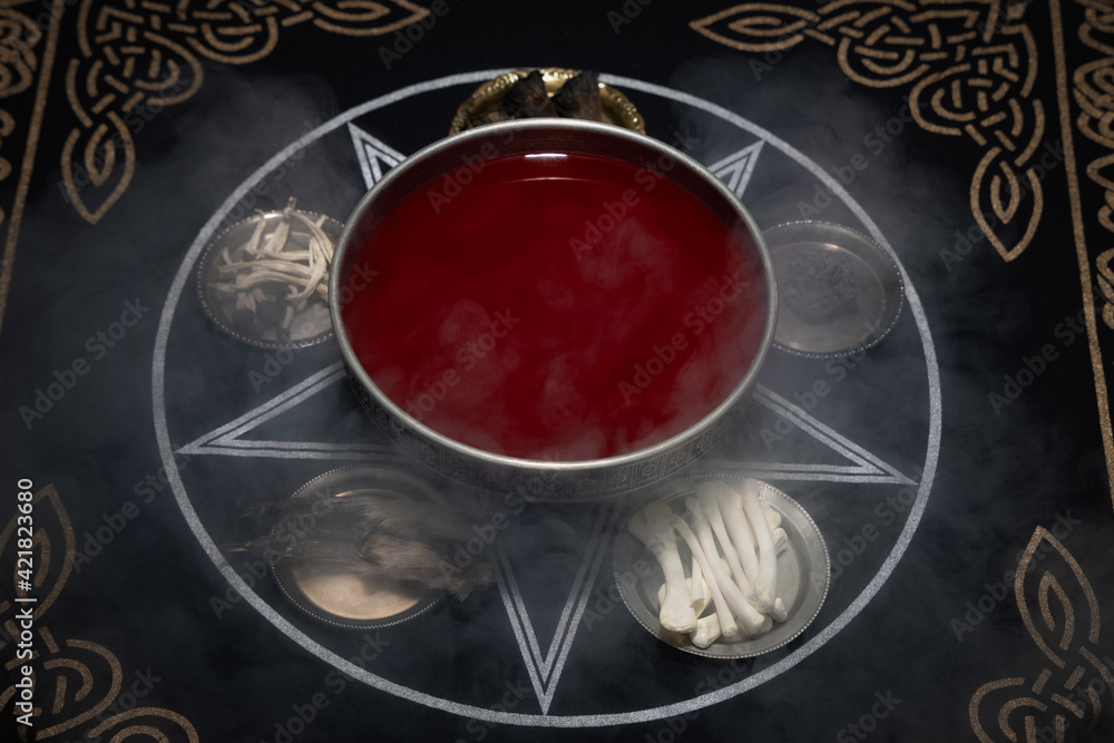 Goblet with blood on ritual table. Dark room with smoke. Black magic ...