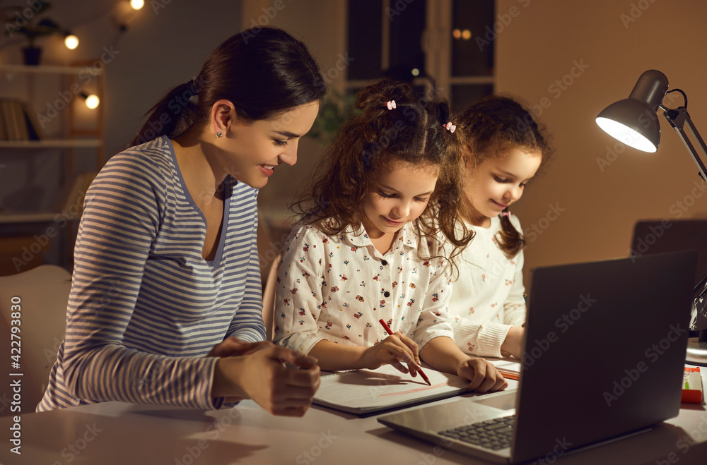 Happy family sitting at desk at home busy with homework. Young parent ...