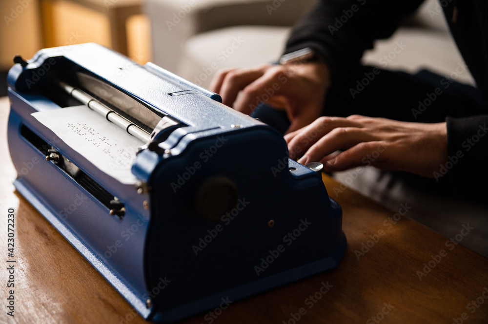 Crop anonymous visually impaired male typing on typewriter with tactile ...