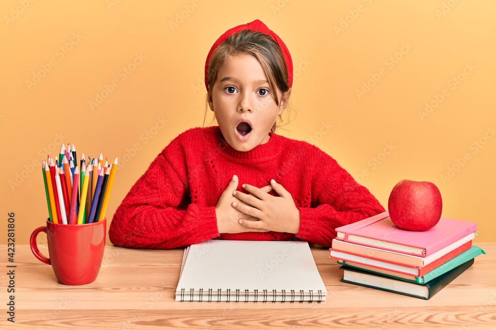 Little beautiful girl sitting on classroom desk scared and amazed with ...