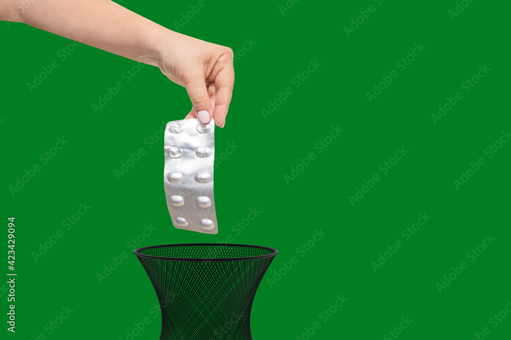 A hand throws a package of medicines into the trash. The concept of ...