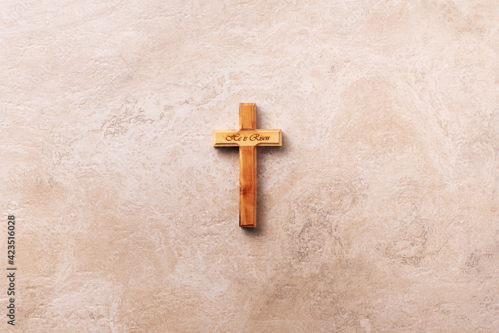 Wooden cross with text He is risen on marble background. Reminder of ...