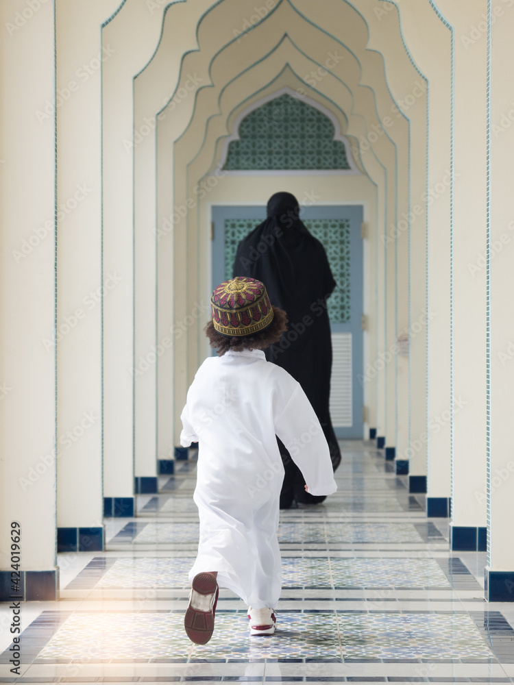 Rear view of Muslim little boy running after mother who wearing black ...