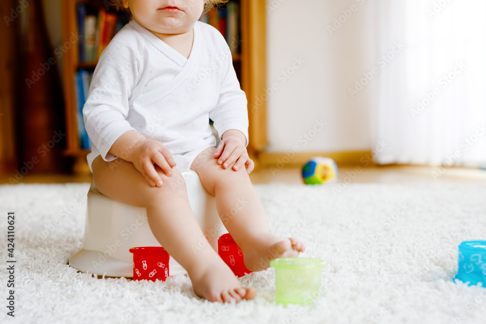Closeup of cute little old toddler baby girl child sitting on potty ...