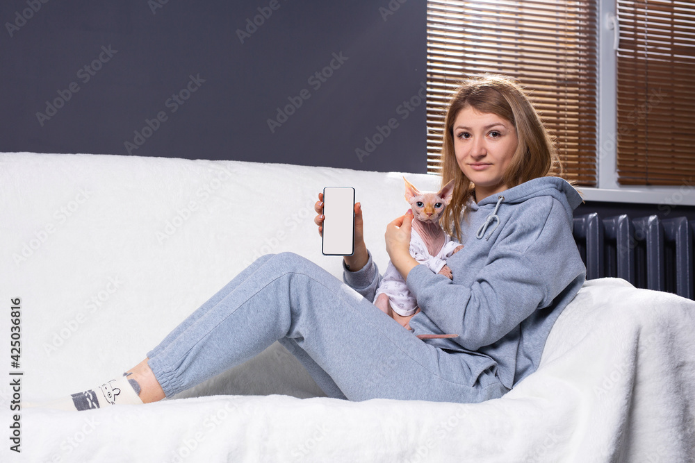 Caucasian blonde girl lying on bed at home with cat , sphinx, pet ...