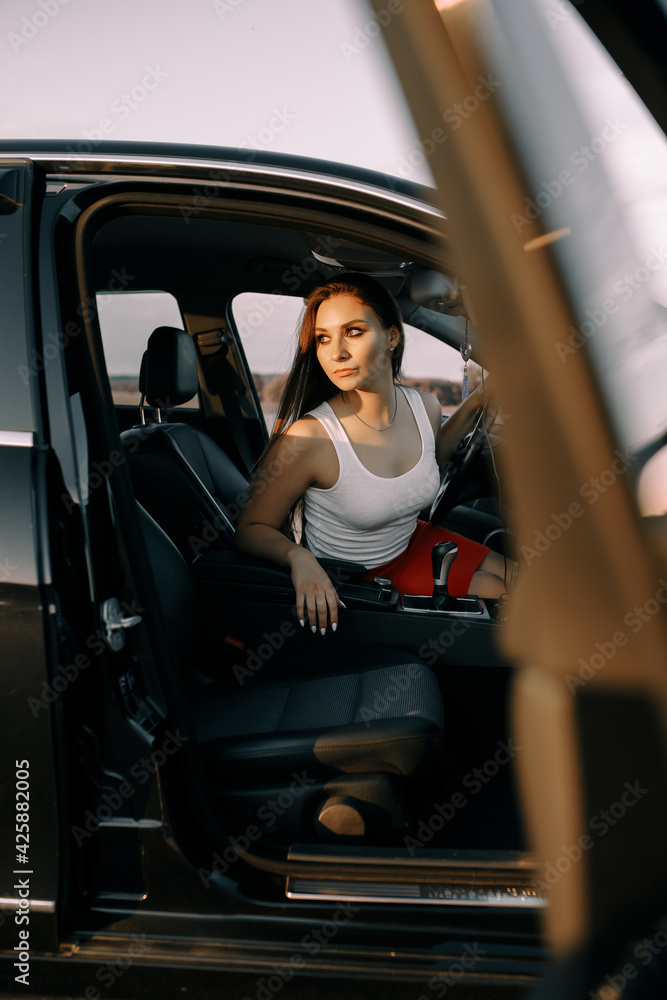 Beautiful young girl driving a car in the evening in the sunset sun on ...