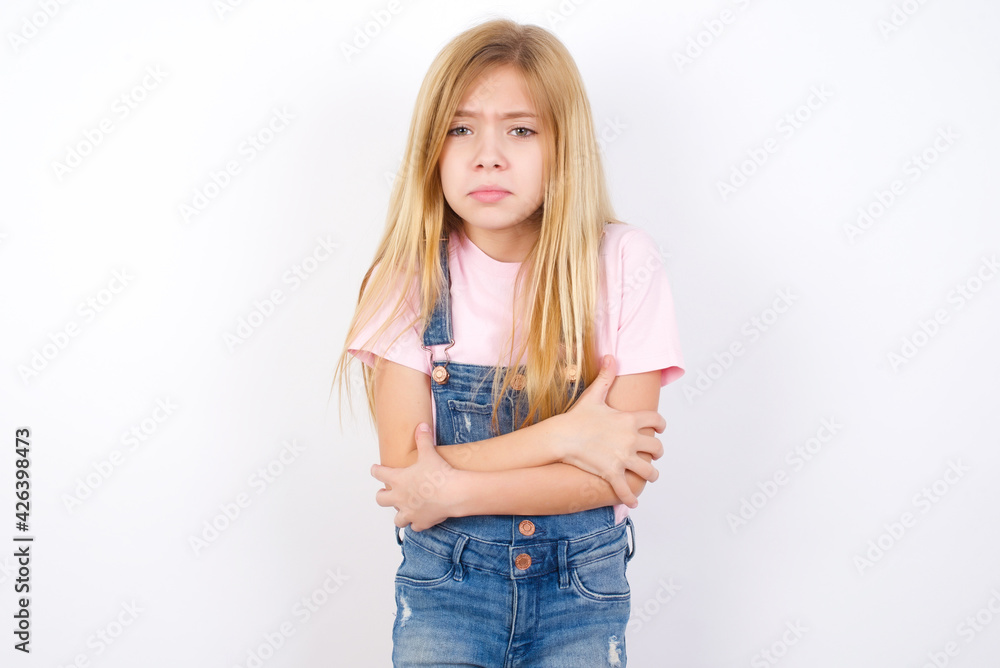 beautiful Caucasian little girl wearing denim overalls over white ...