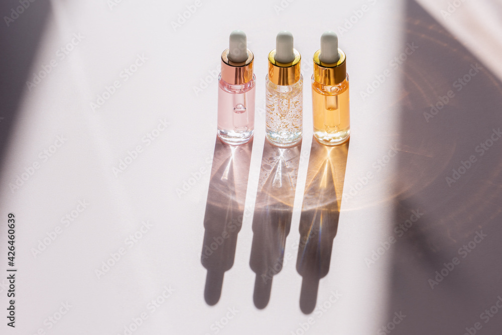 Glass bottles of beauty serum or oil or lotion products with shadows on ...