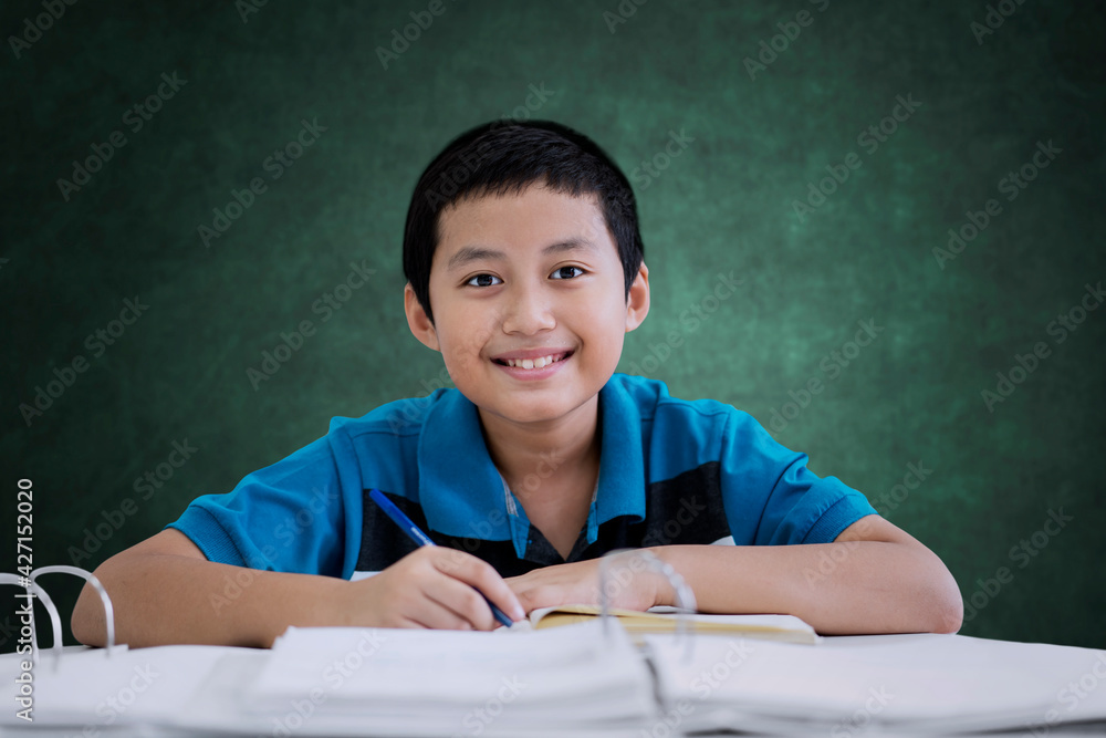 Foto de Stock Asian preteen boy taking notes in the classroom | Adobe Stock