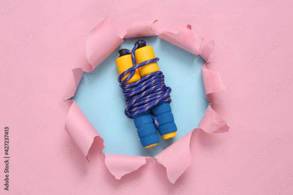 Skipping rope through torn hole on blue-pink pastel background. Concept ...