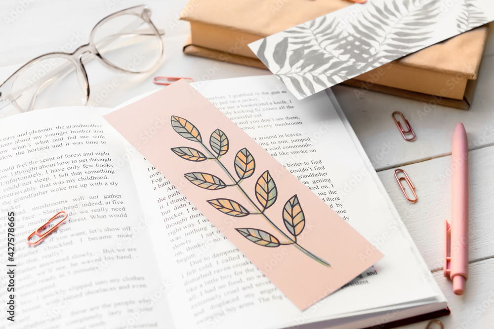 Books with bookmarks, glasses and stationery on light wooden background ...