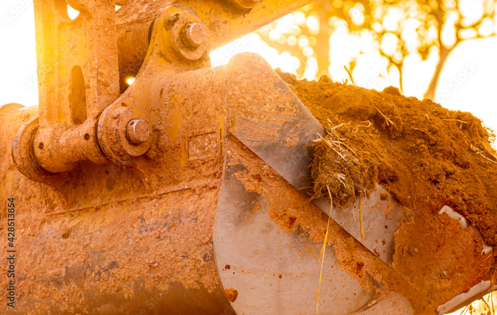 Backhoe working by digging soil at construction site. Bucket of backhoe ...