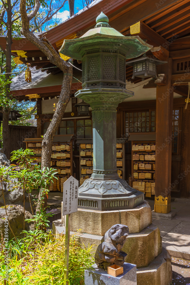 Copper lantern and stone monument Maneki-ishi depicting the shape of a ...