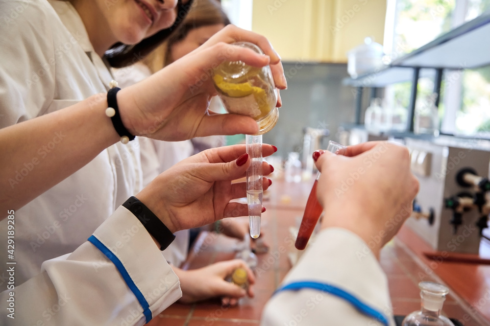 Girl students conducting scientific experiment in chemistry laboratory ...