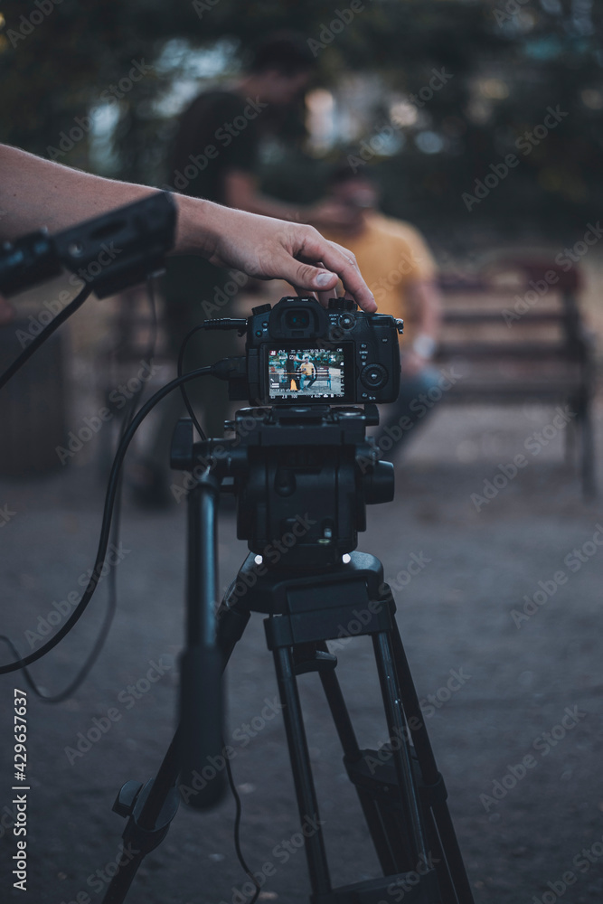 Holding a static camera recording button in a park. Scene with younger ...