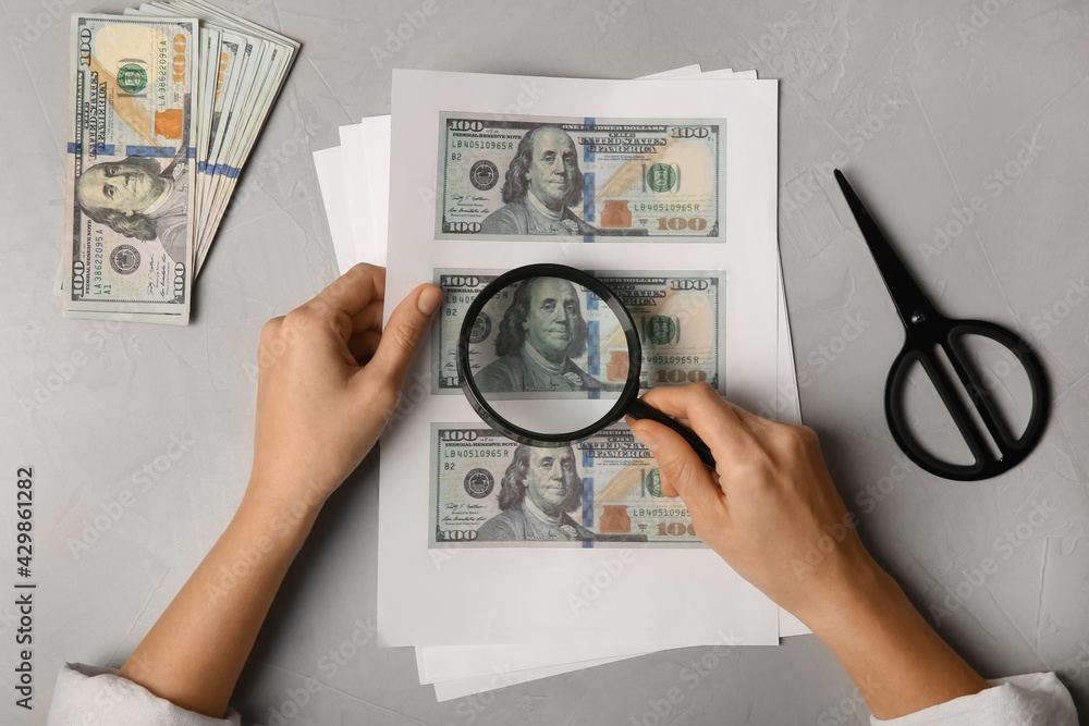 Stock-Foto „Counterfeiter examining sheet of paper with dollar ...