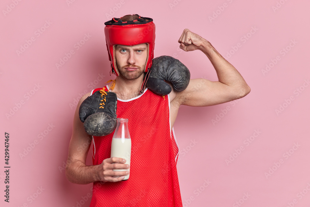 Стоковое фото «Serious male boxer raises arm shows biceps drinks fresh ...