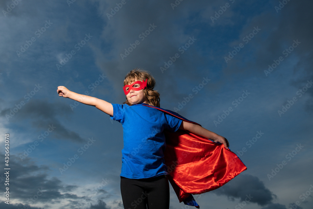 Superhero kid against dramatic blue sky background. Strong super hero ...