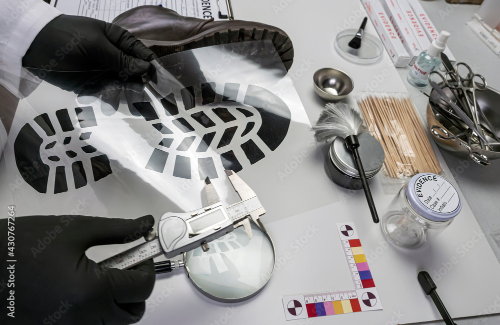 Police scientist investigates with a scale on a shoe sole tape tread ...