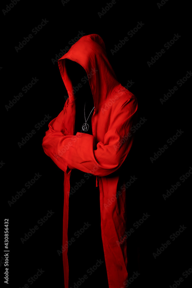 Mystery man in a red hooded cloak in the dark. Unrecognizable person. Hiding face in shadow ...