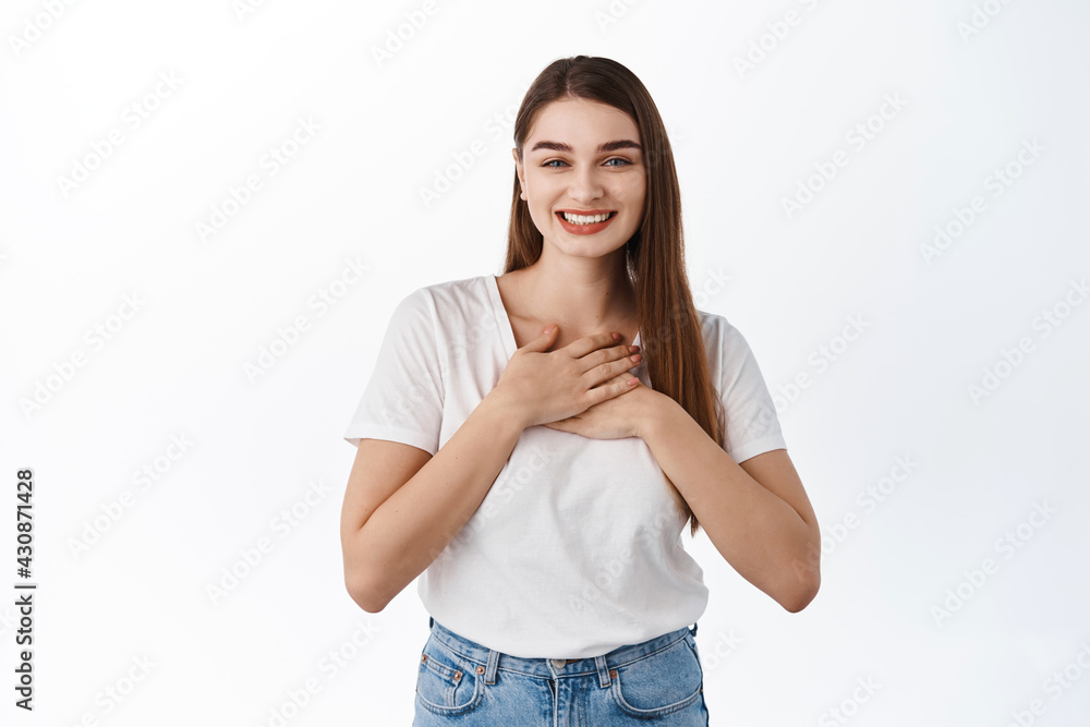 Smiling thankful girl appreciate nice gesture, holding hands on heart ...