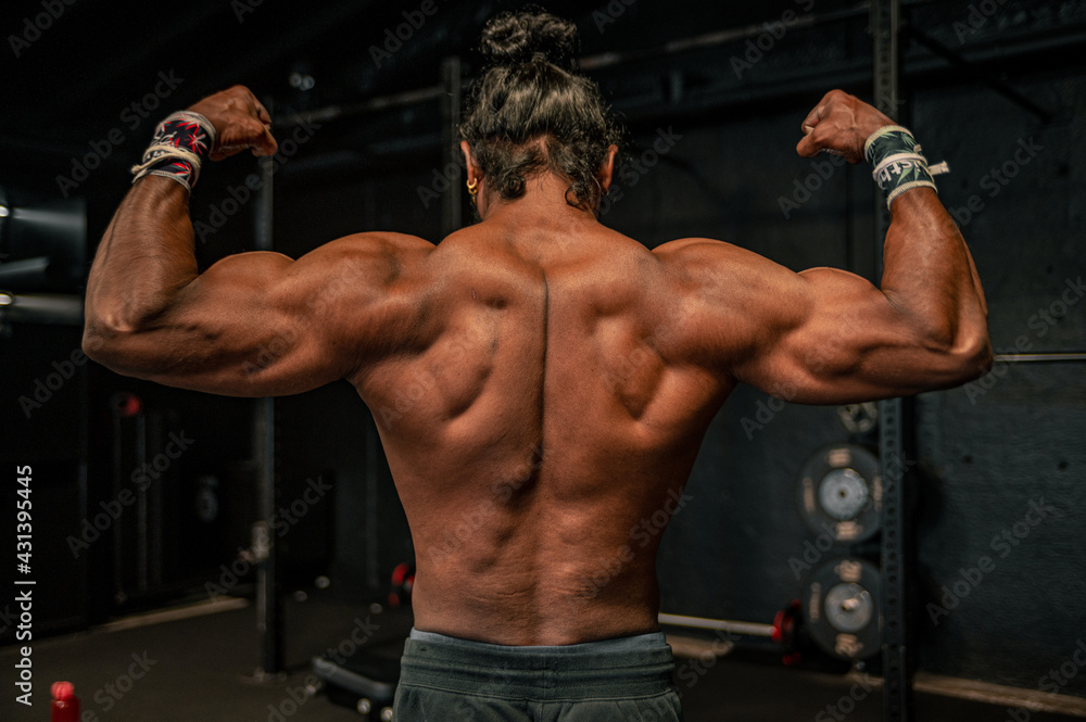 Adult bodybuilder man with long hair showing his back muscles and ...