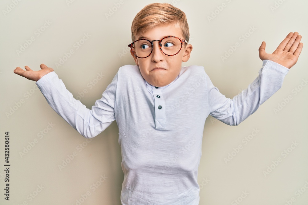 Little caucasian boy kid wearing casual clothes and glasses clueless ...