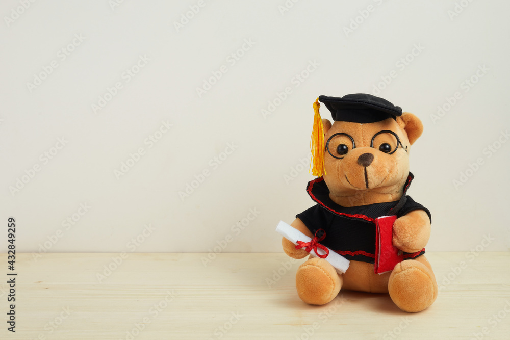 Cute teddy bear with nice graduation clothes and diploma on wooden ...