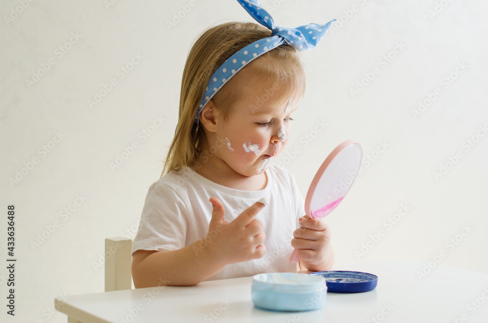 Fotografie Little cute two years old girl with face cream on her cheeks ...