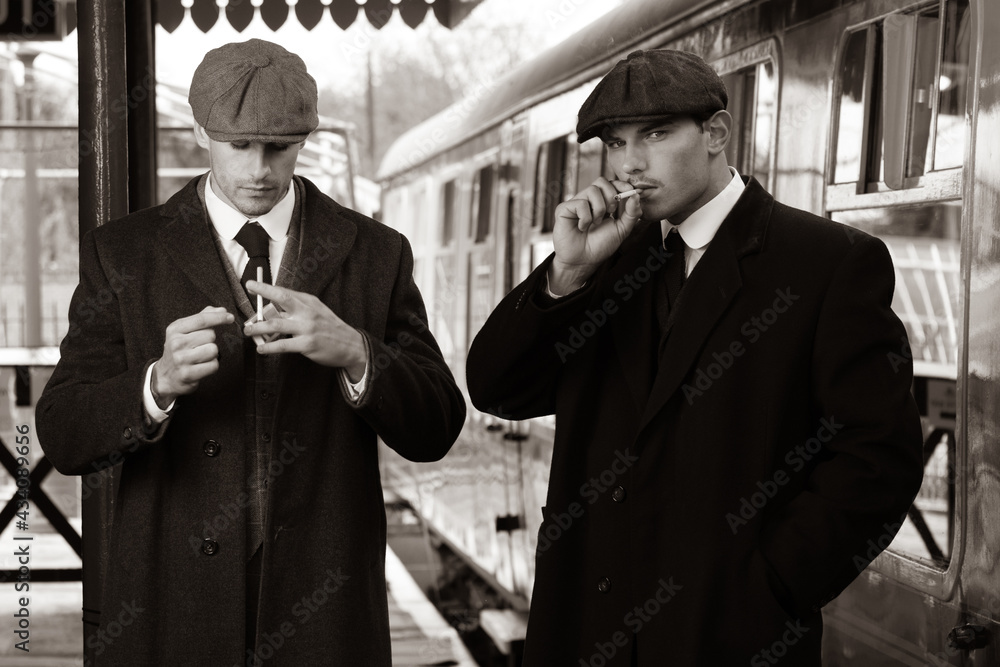 Handsome English gangsters smoking at railway station with train in the ...