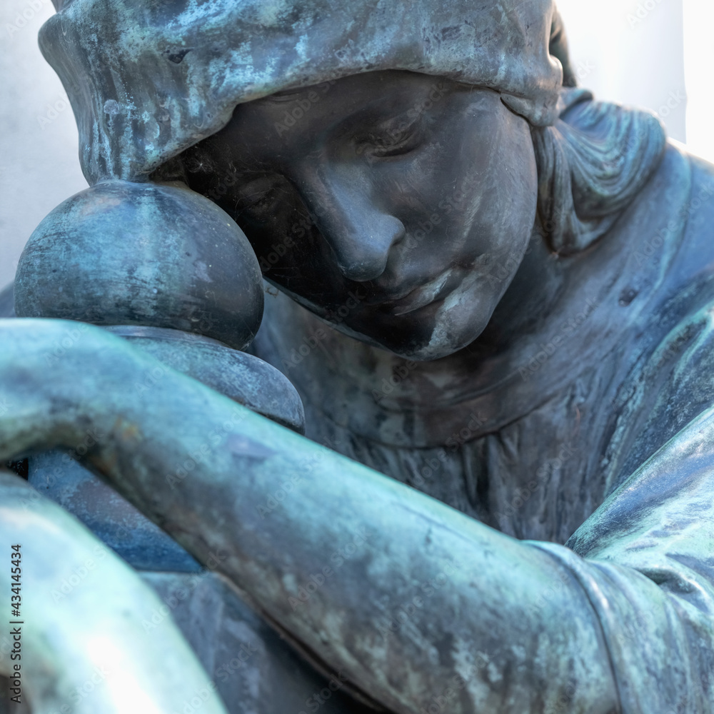 Close up fragment of an ancient iron statue of sad and desperate woman ...