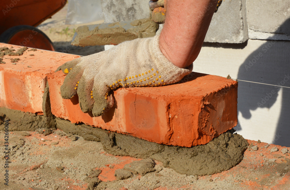 Masonry construction. A bricklayer is laying bricks on mortar using a ...