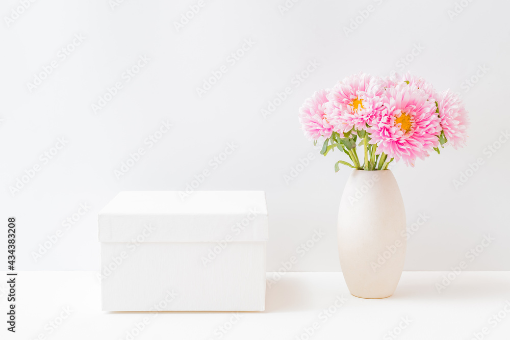 Empty white box and pink flowers in a vase on a light background ...