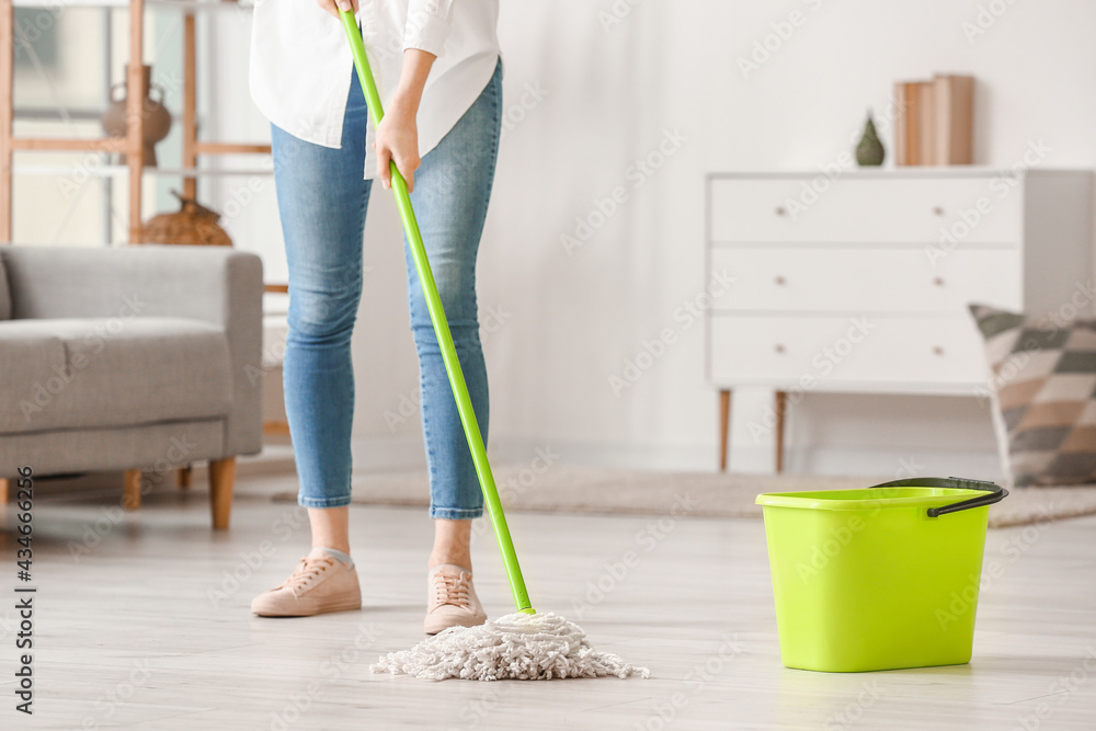 Young woman mopping floor in her flat Stock Photo | Adobe Stock