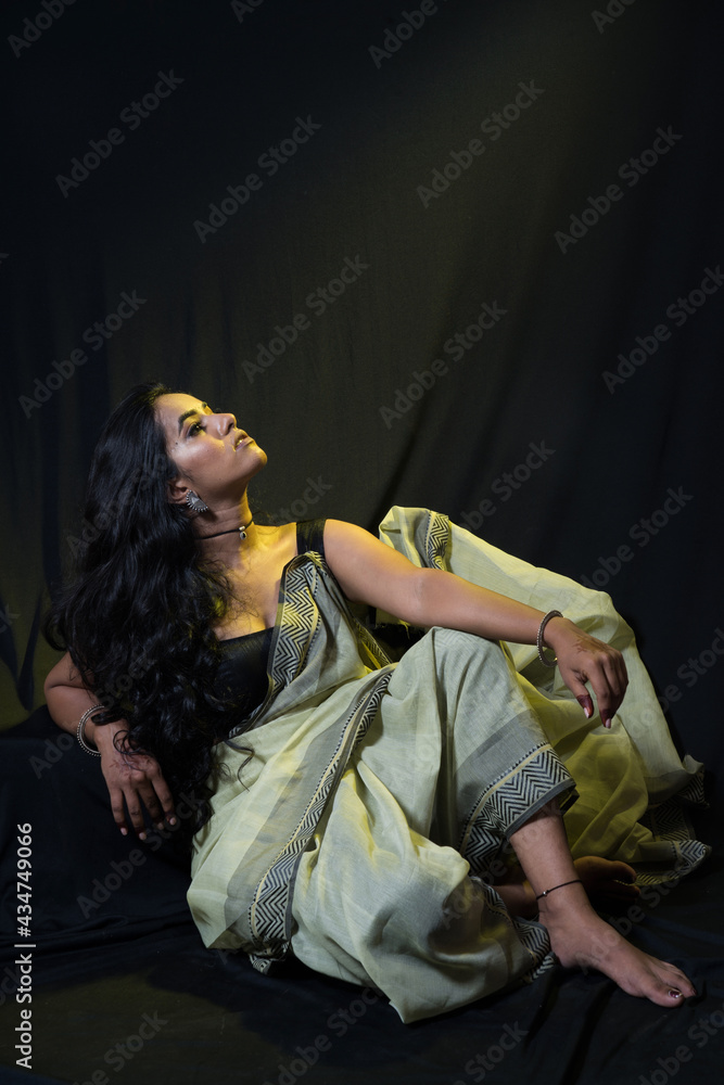 Young Indian fashion model in Saree on black background. Sitting on ...