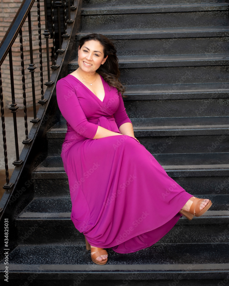 Full body portrait of a gorgeous lady posing on stairs in a pink purple ...