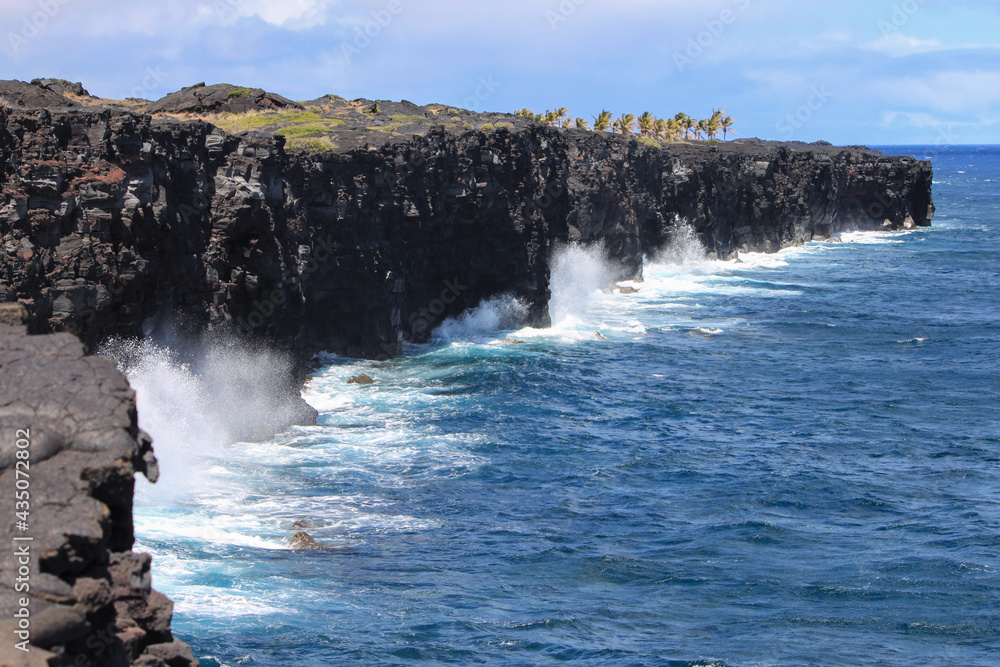 Breakers striking against the black volcanic lava cliffs along the ...